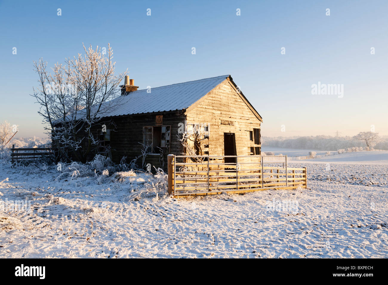 An old isolated run down wooden cottage in a snow covered Winter field ...