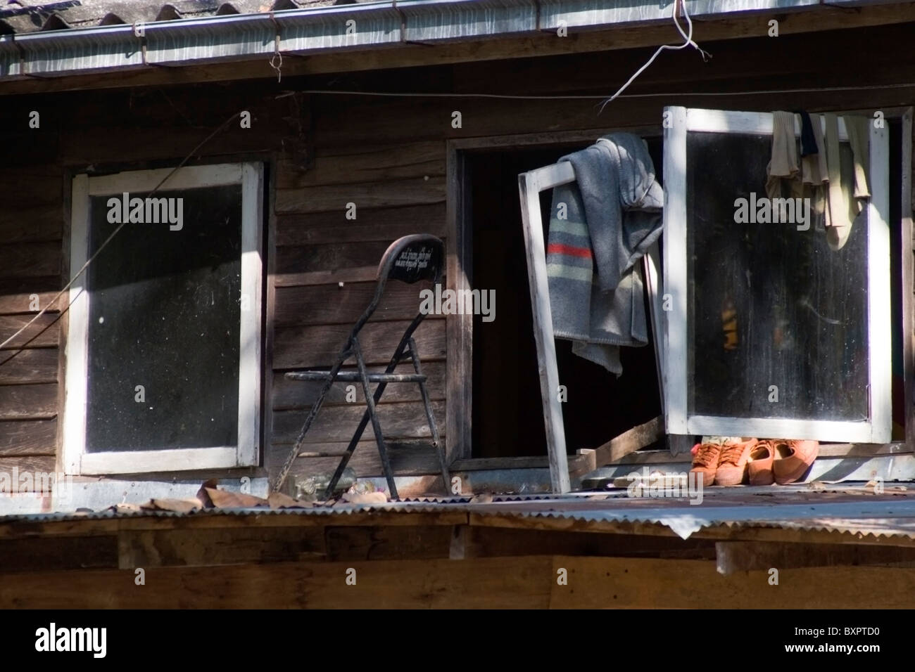 A metal folding chair is placed between windows on a rundown and ...