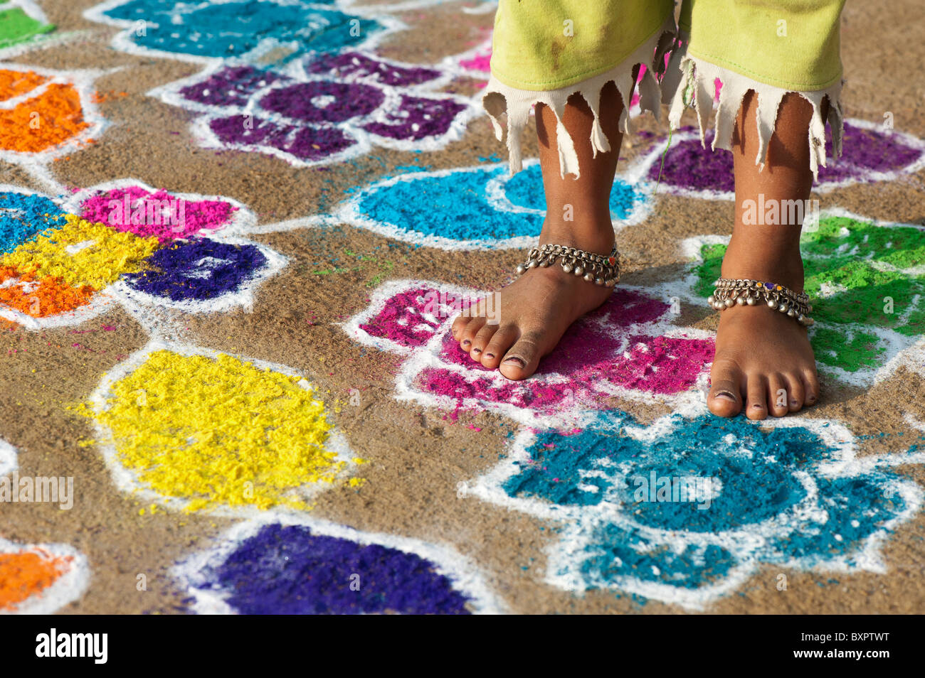 Indian childs bare feet standing on a Rangoli coloured powder ...