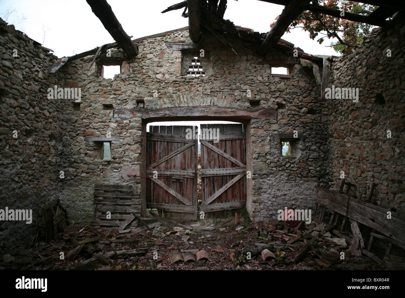 The inside of a derelict stone building, facing wooden double doors ...