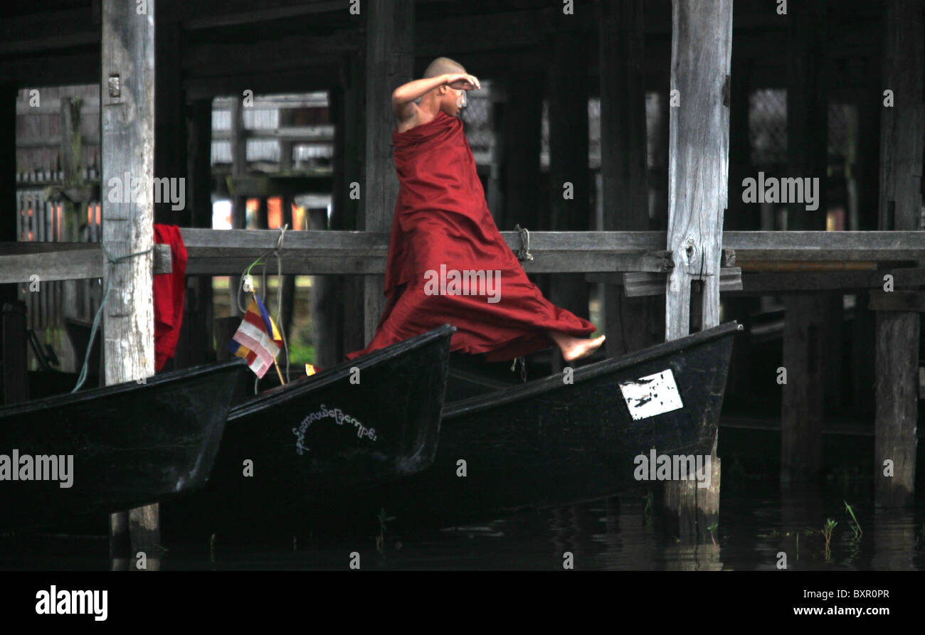 A novice monk jumps between boats at a floating monastry on Inle Lake ...
