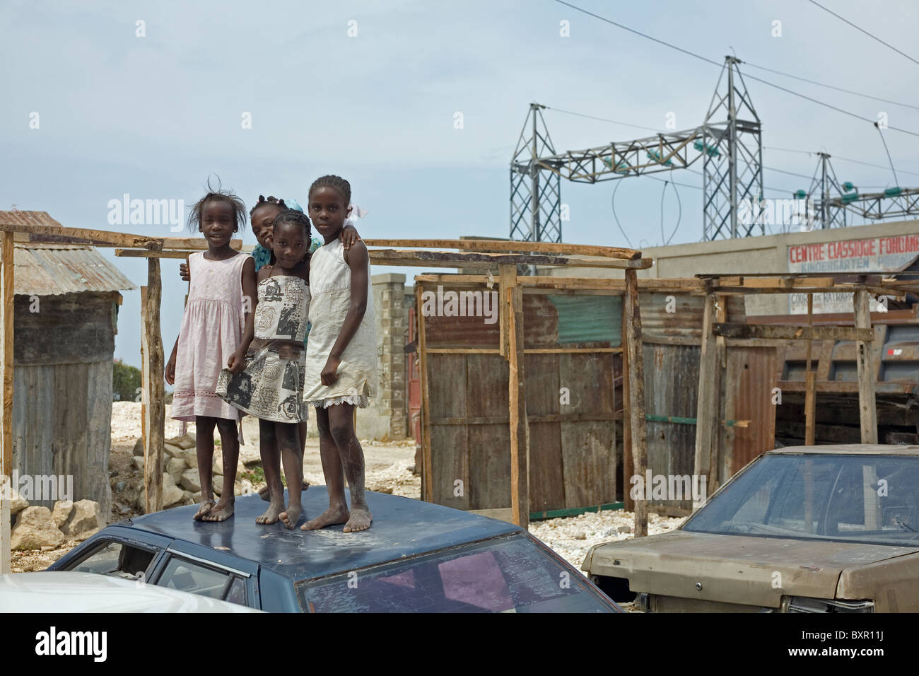 Barefoot Haitian girls play on the roof of a car in Carrefour, Port-au ...