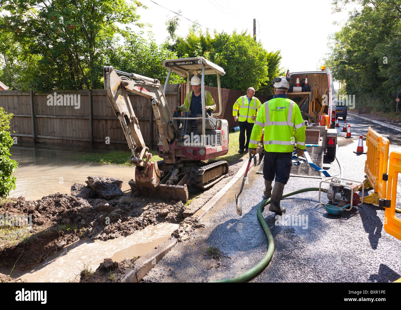 workers from MAY GURNEY digging a hole next to a road to repair a burst ...