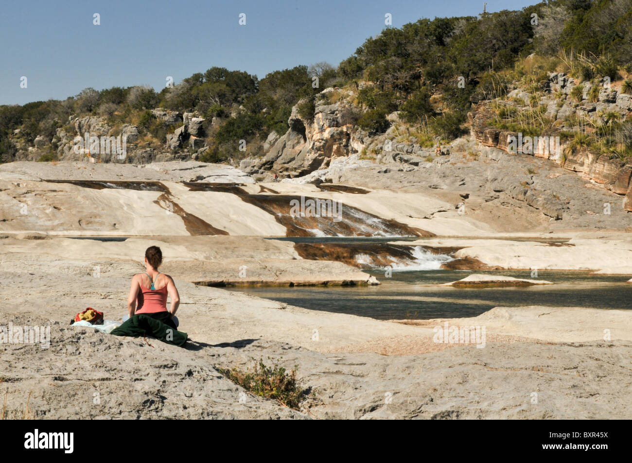 Woman meditating viewing paleozoic rocks exposed in Pedernales Falls ...