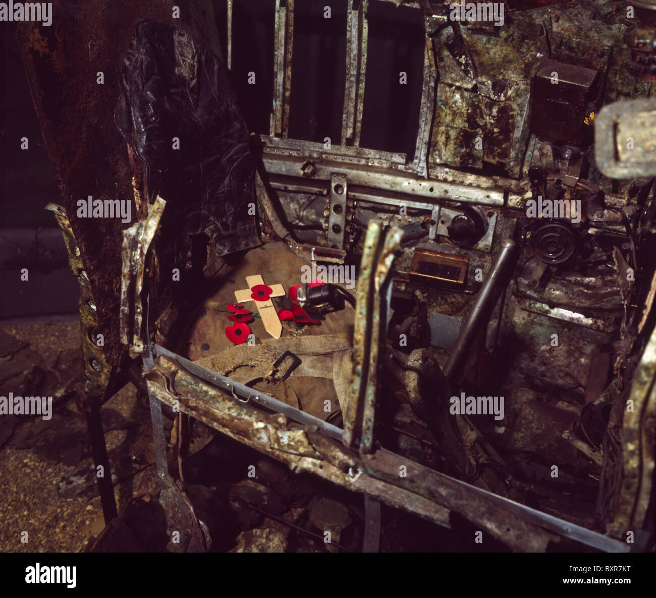 A poppy on a small wooden cross in the cockpit of a burnt out wreck of ...