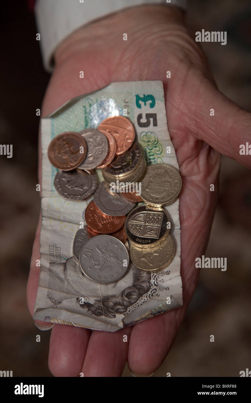 An old aged pensioner holding out his hand with a five pound note and ...