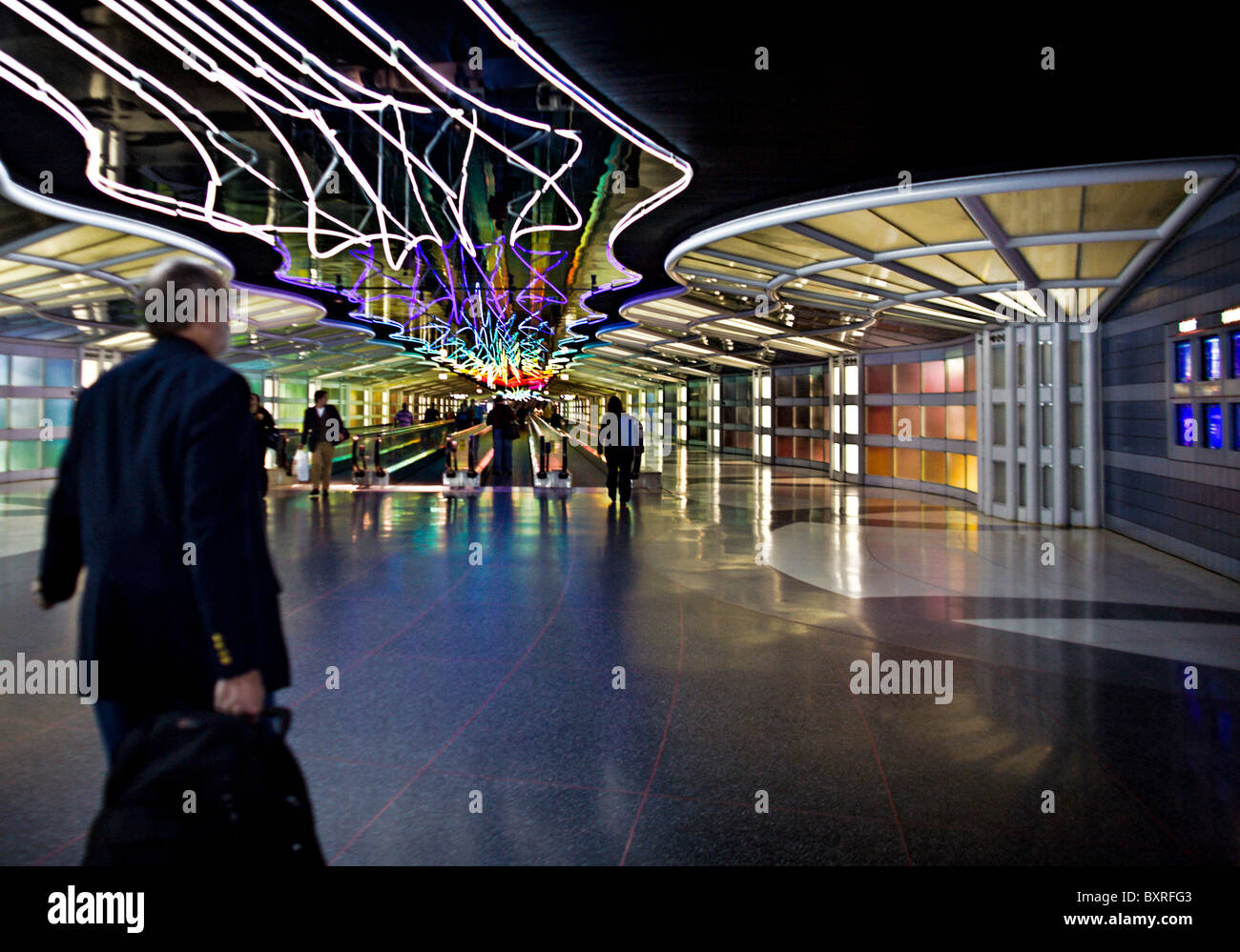 CHICAGO, ILLINOIS: Busy travelers on a moving sidewalk illuminated by ...