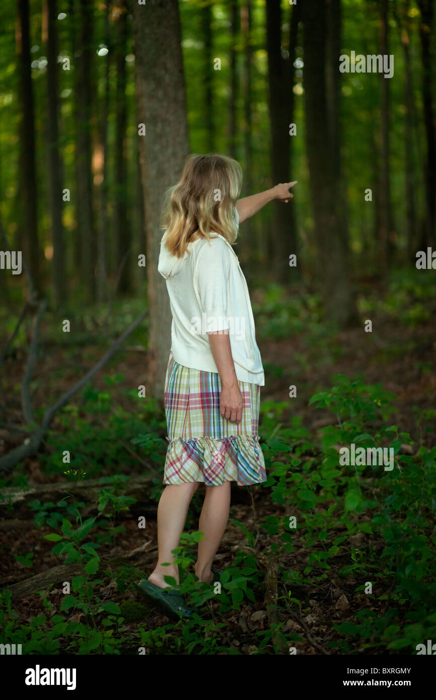 Young woman in woods pointing her finger into the distance Stock Photo ...