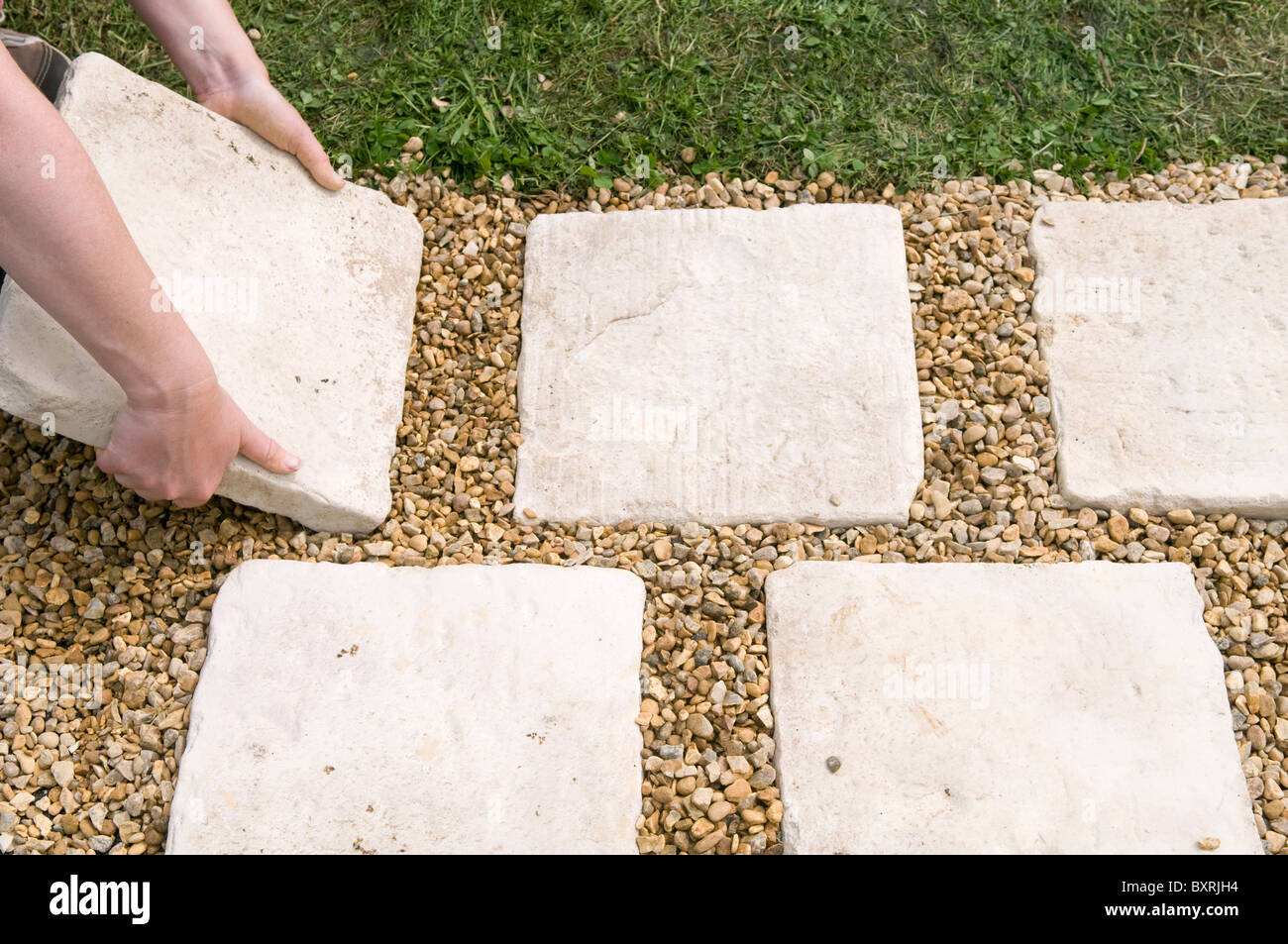 Hand positioning paving slabs on ground Stock Photo - Alamy