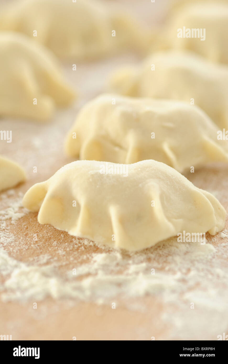 Raw pierogi (traditional polish dumplings) being prepared for boiling ...