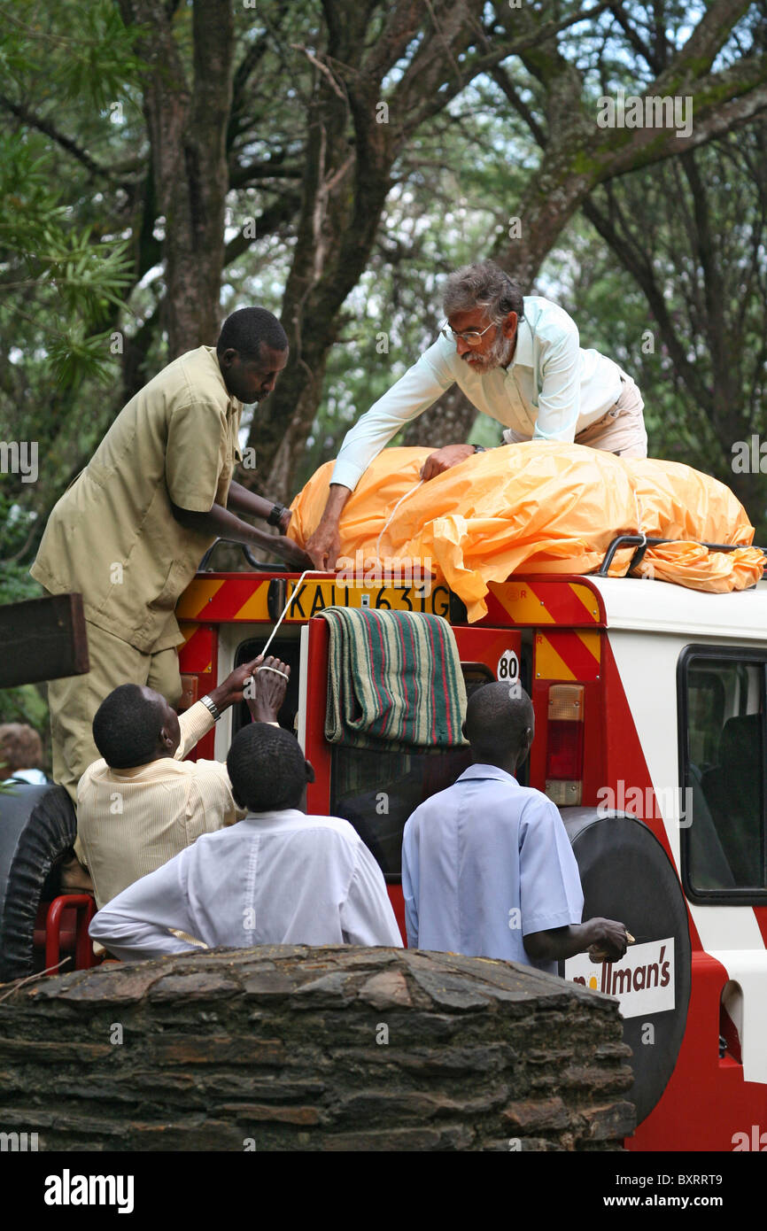 Safari tour leader and staff cover and secure guests' luggage on the ...