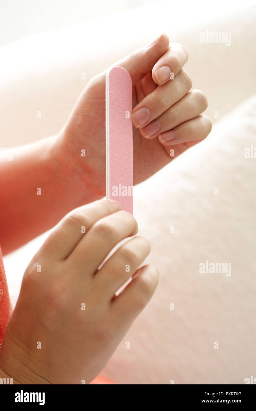 Woman filing nails using pink nail file Stock Photo - Alamy