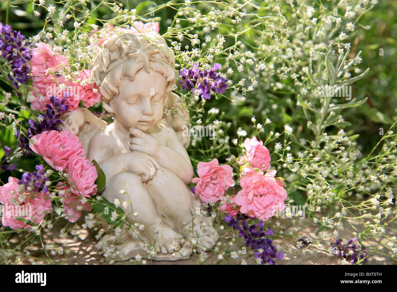 Little angel figurine in the flower bed Stock Photo - Alamy