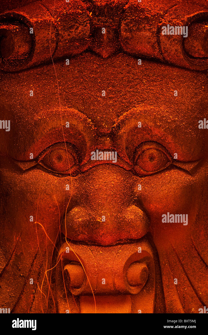 Decorative carved stone face at the back of a fireplace, glowing by the ...