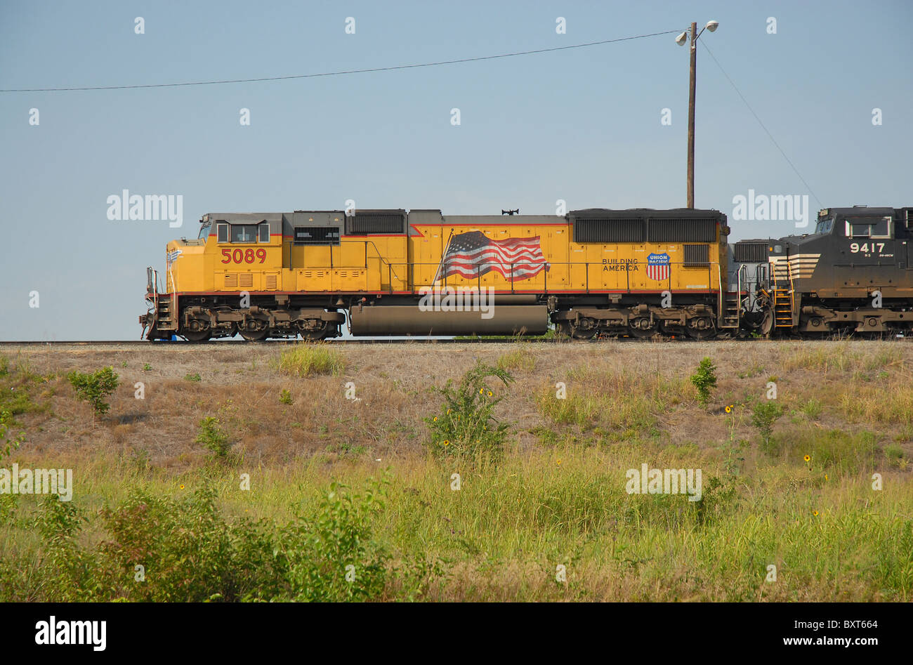 A yellow railroad engine displaying a United States flag on the side ...