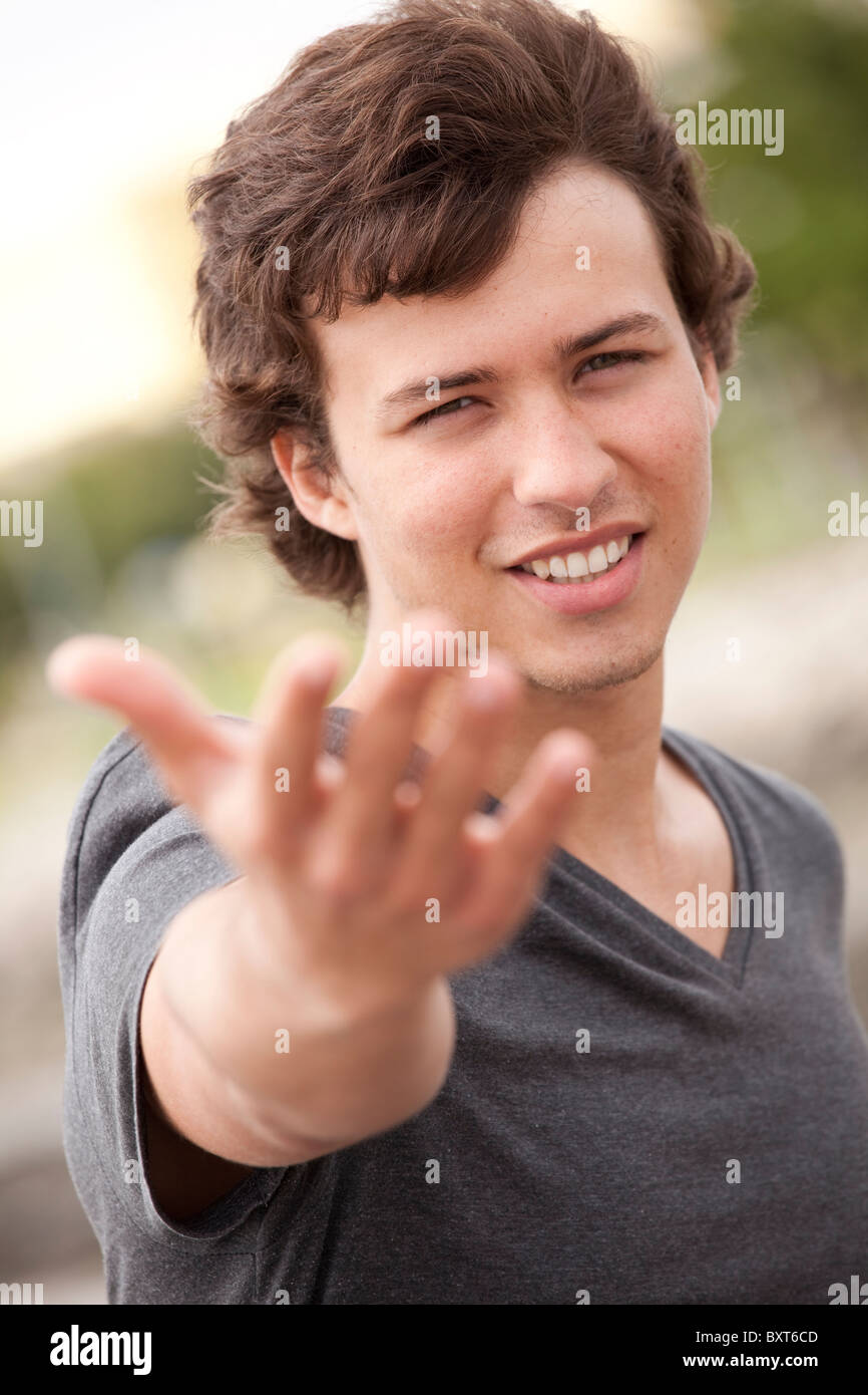 young man smiling and giving you a hand Stock Photo - Alamy