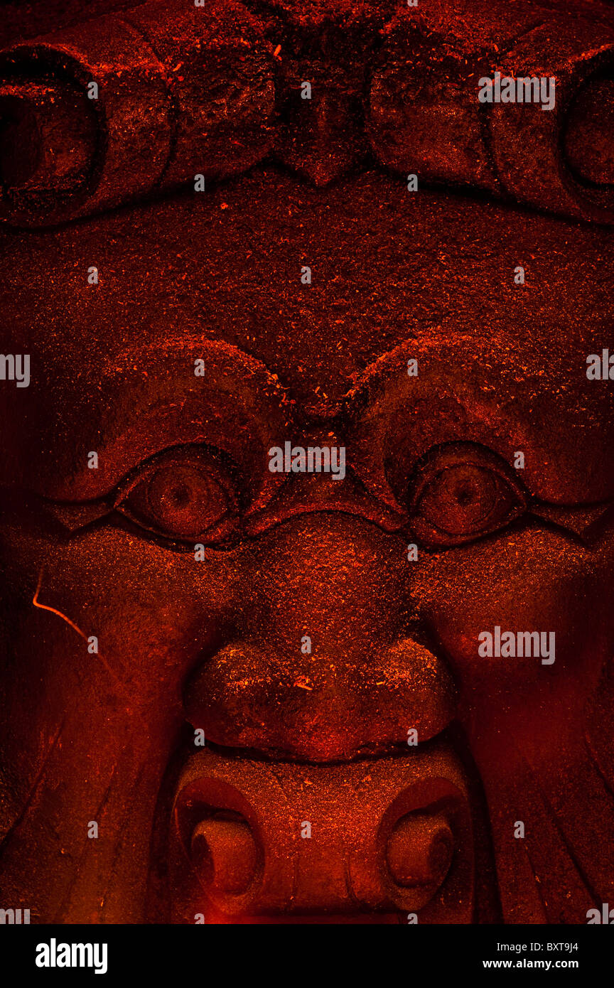 Decorative carved stone face at the back of a fireplace, glowing by the ...