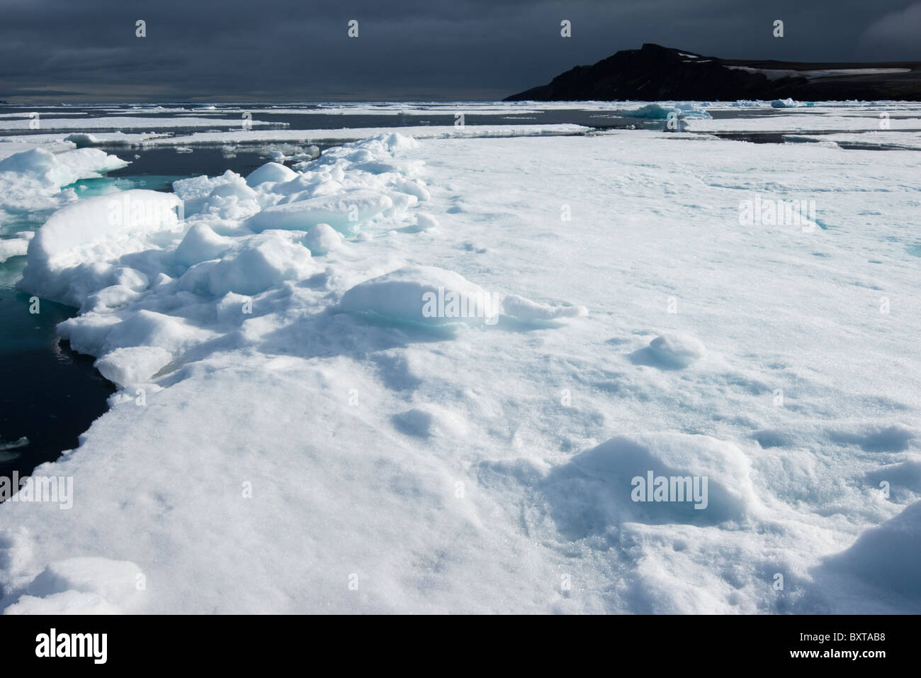 Norway, Svalbard, Morning sun lights snow on top of melting sea ice ...