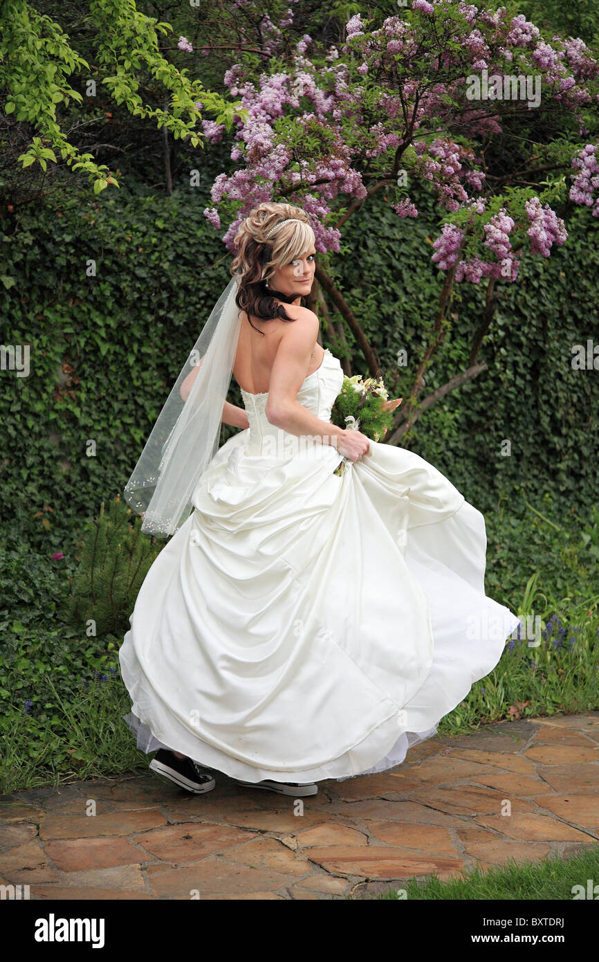 pretty blond bride walking down garden path in wedding dress Stock ...