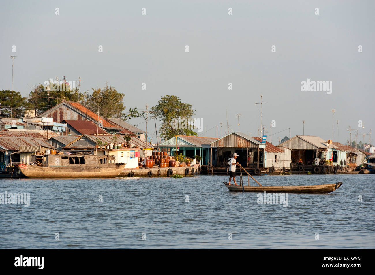 Canoe crossing the Hau Giang River (Bassac River) lined with floating ...