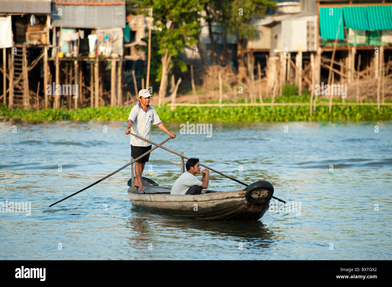 Canoe crossing the Hau Giang River (Bassac River) lined with floating ...