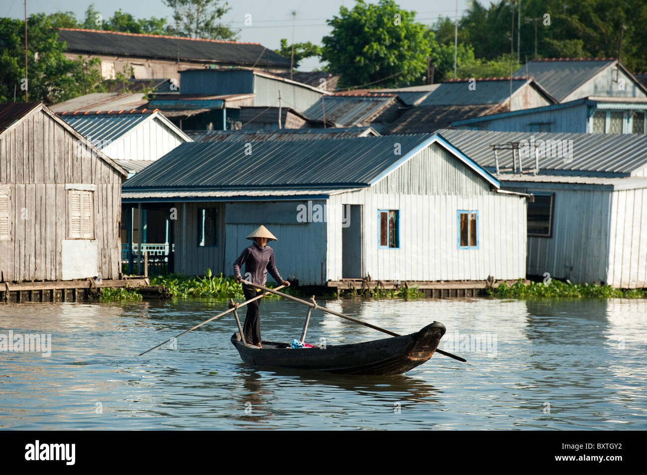 Canoe crossing the Hau Giang River (Bassac River) lined with floating ...