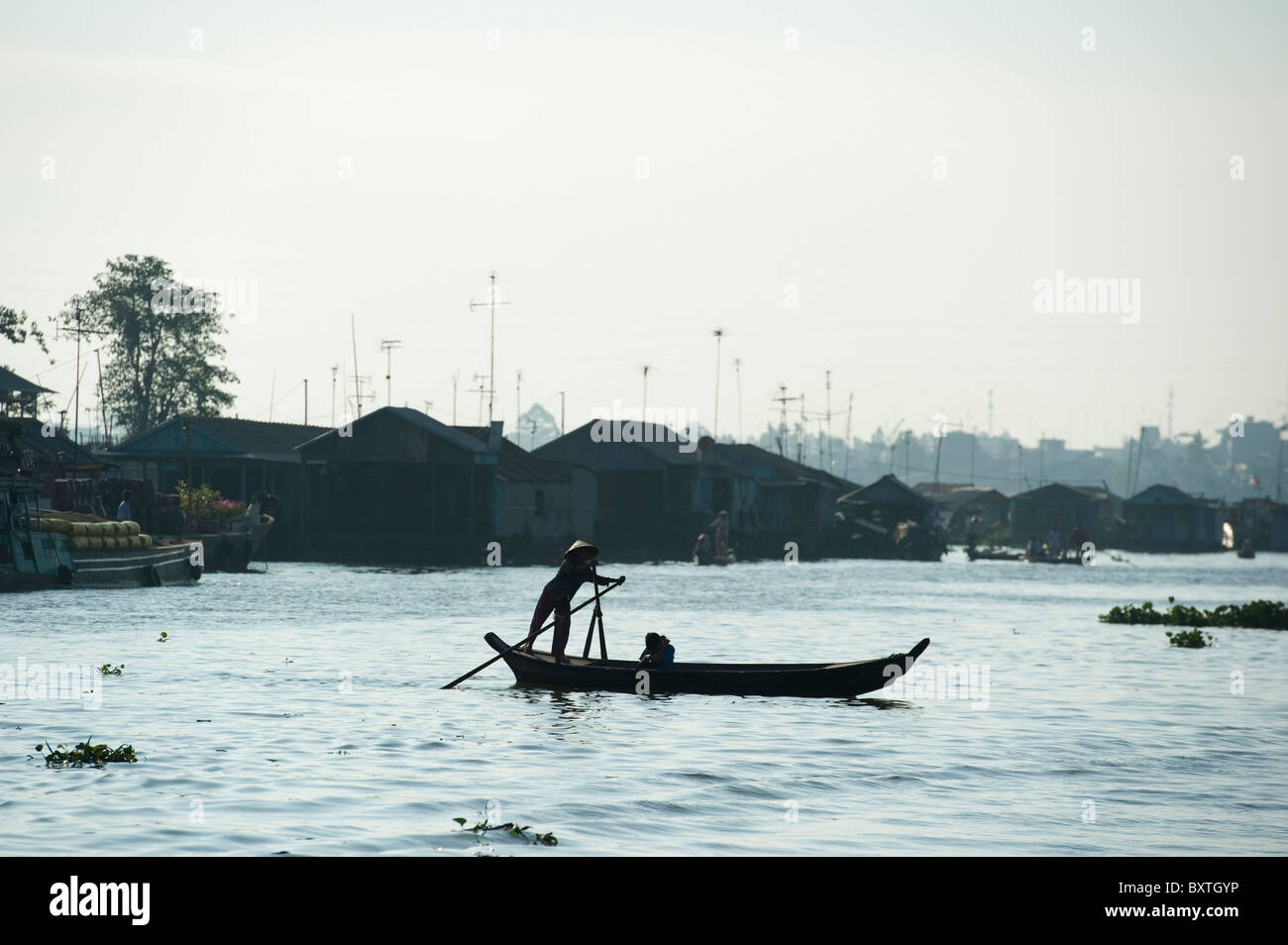 Canoe crossing the Hau Giang River (Bassac River) lined with floating ...