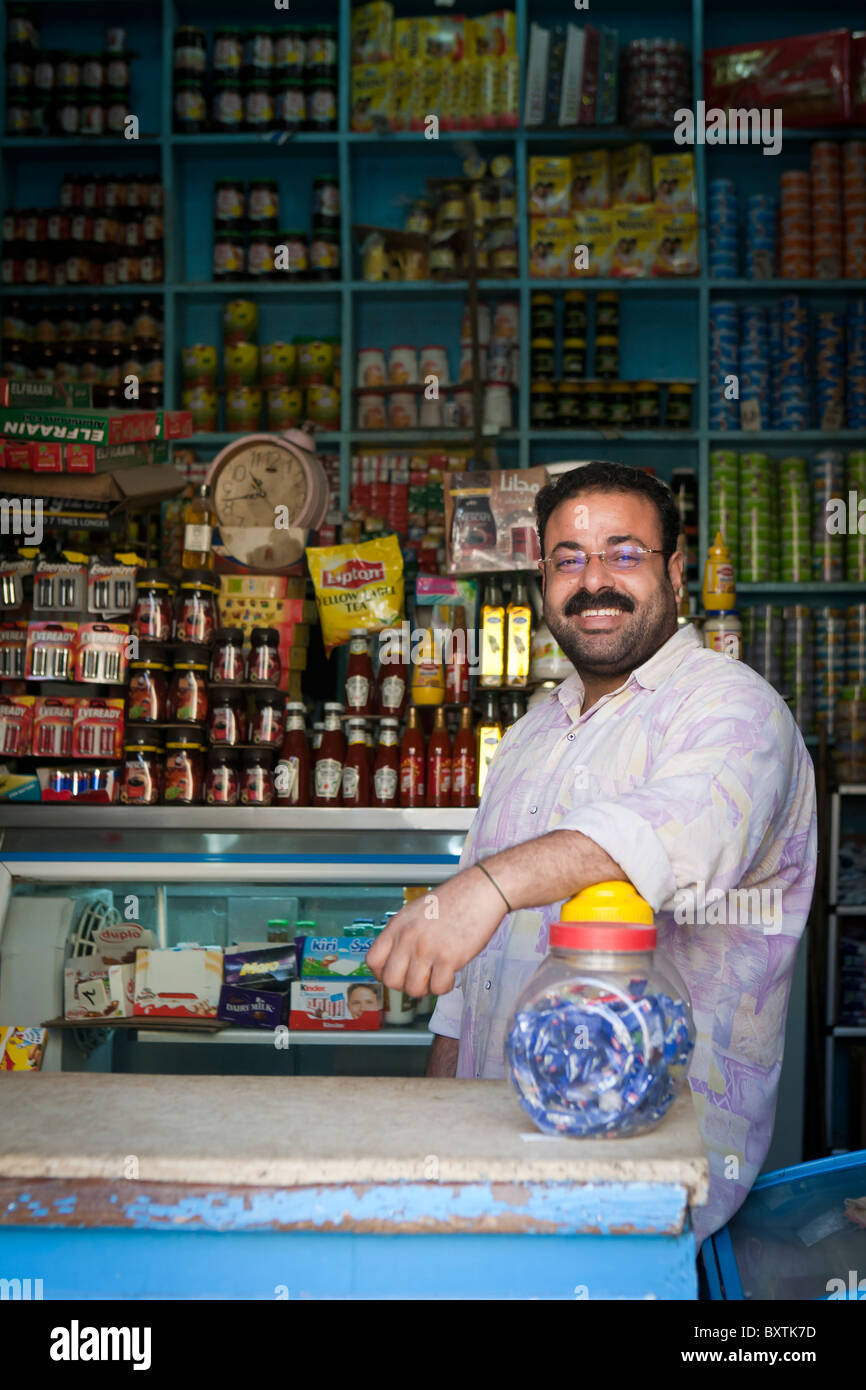 Happy smiling shop owner leaning on his shop counter at a local street ...