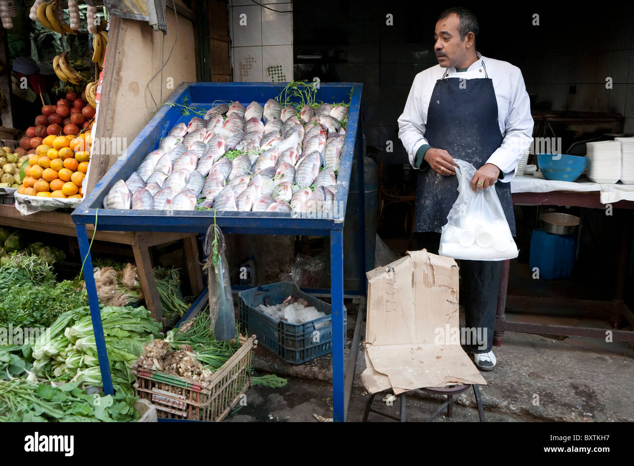 Fishmonger standing by fish outside at a local street market, Luxor ...