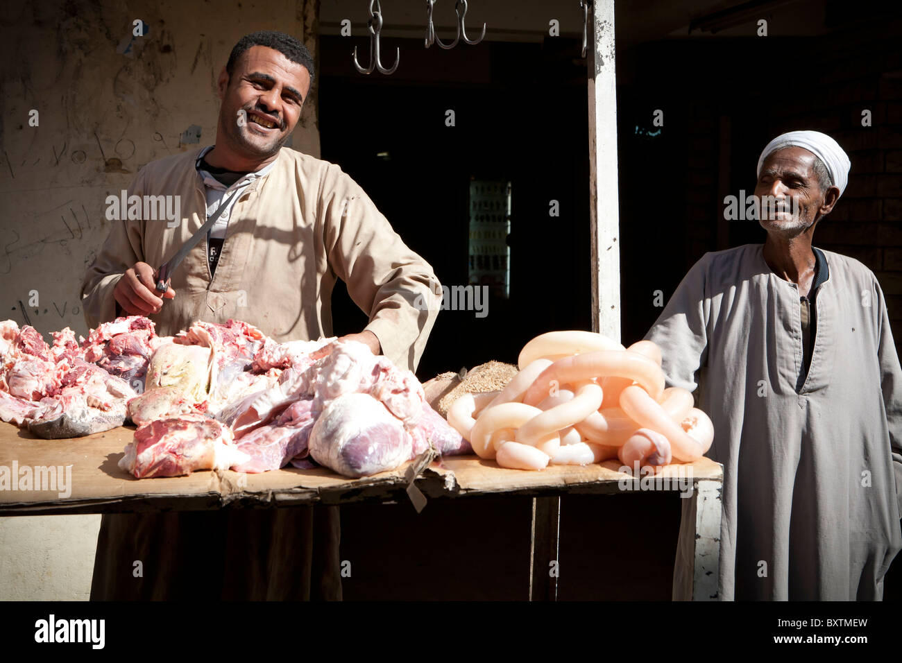 Butcher and friend, cutting various meats on table outside at a local ...
