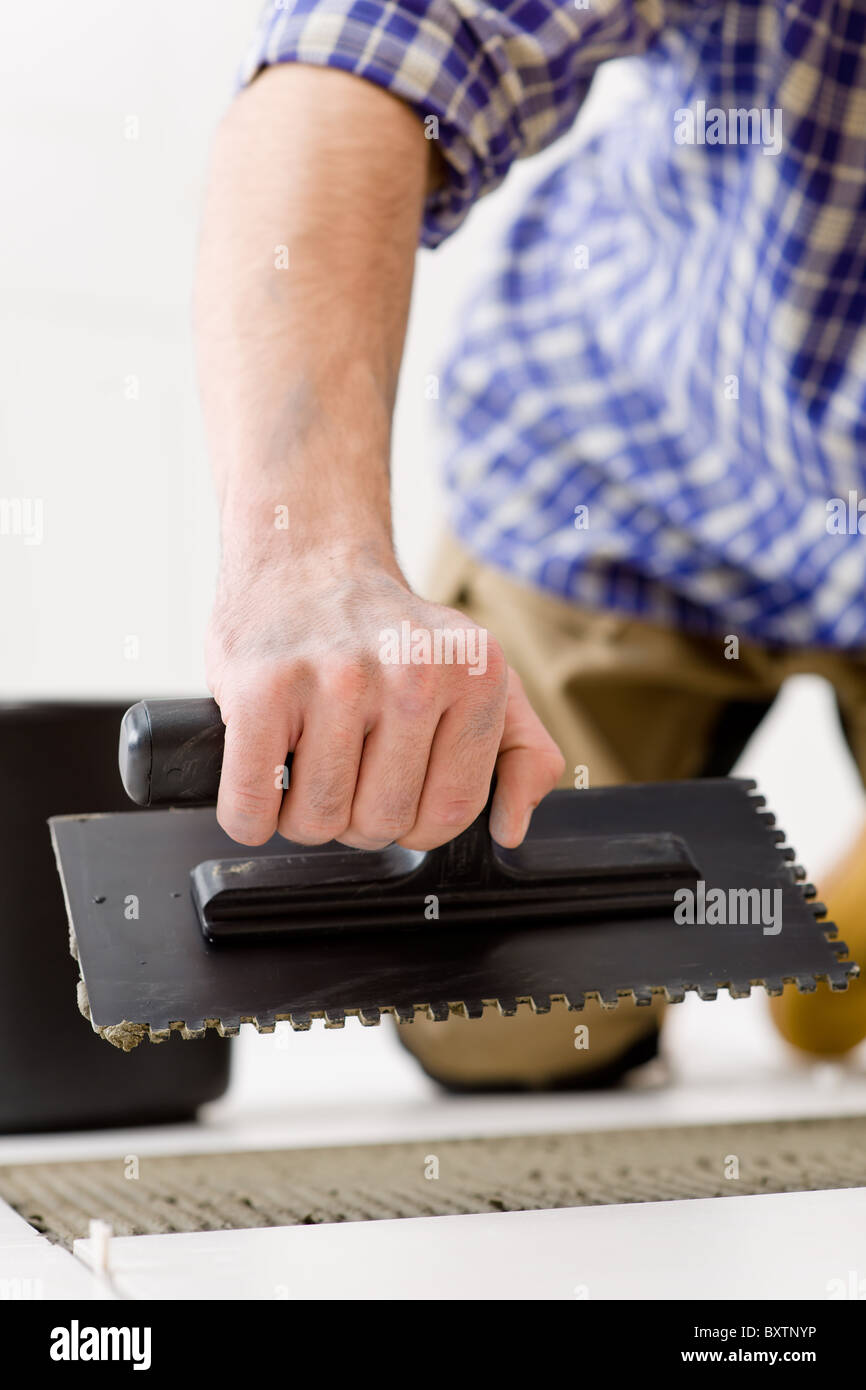 Home improvement, renovation - handyman laying tile, trowel with mortar ...