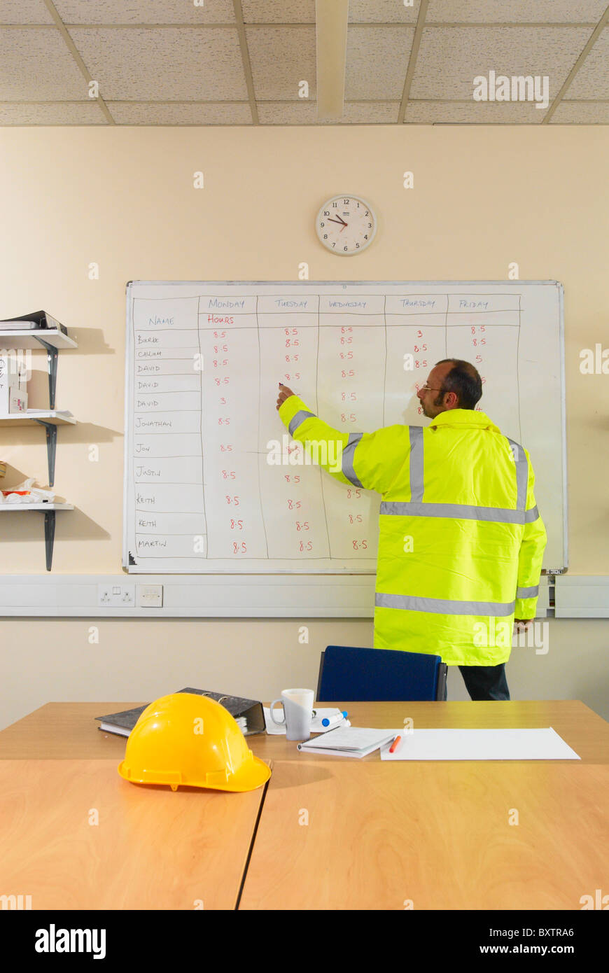Construction worker pointing at timesheet schedule on whiteboard Stock ...