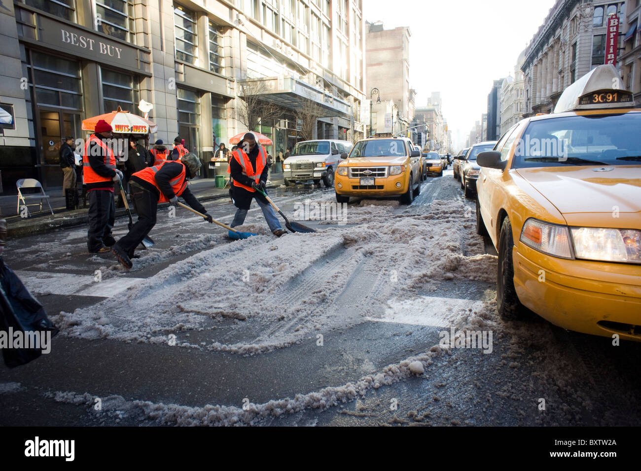 Workers hired by the city dig out snow to clear the streets in the ...