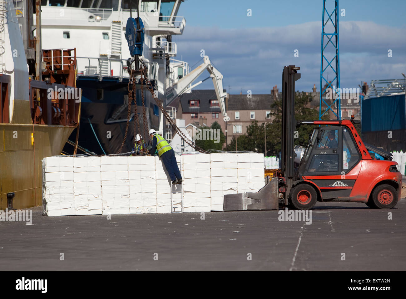 Forklift transferring paper cargo to warehouse from ship cargo hold ...