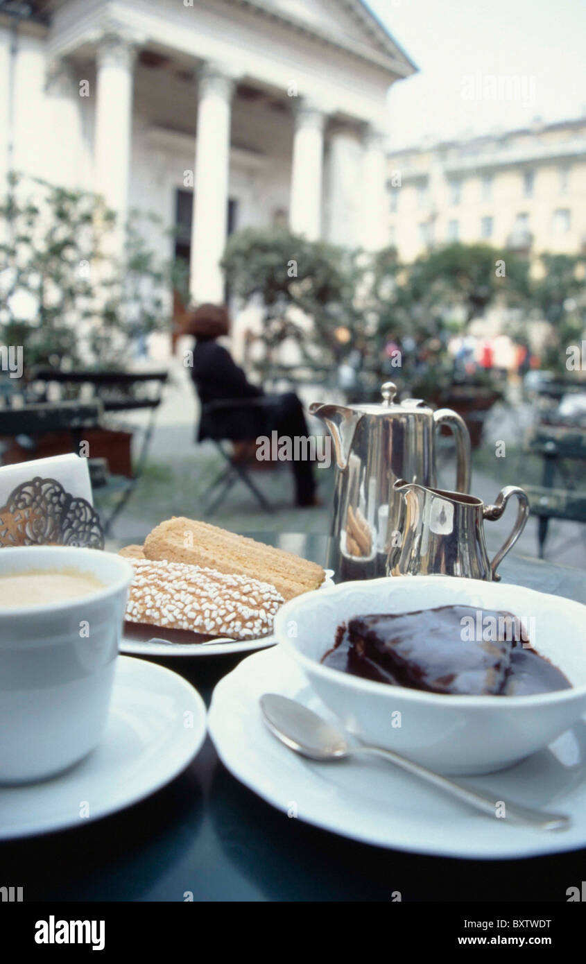 Woman Sitting At Cafe Table With Hazelnut Cake And Chocolate Sauce At ...
