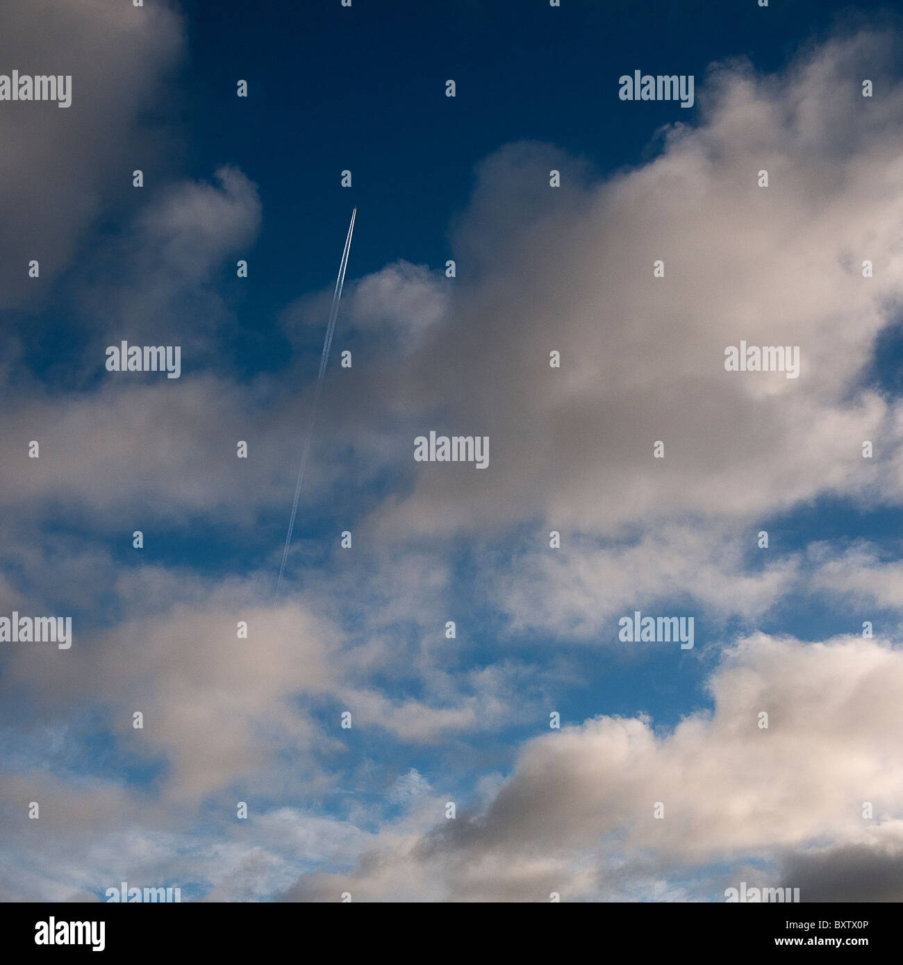 Jet and vapourtrail against a blue and cloudy sky Stock Photo - Alamy