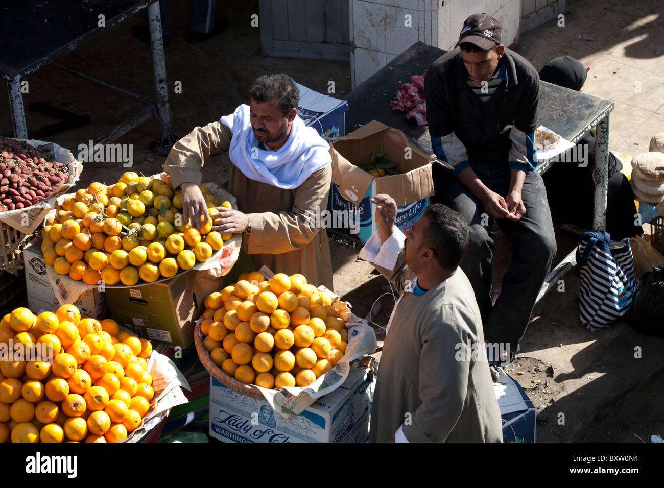 Vegetable seller selecting fruit at a local street market, Luxor, Egypt ...