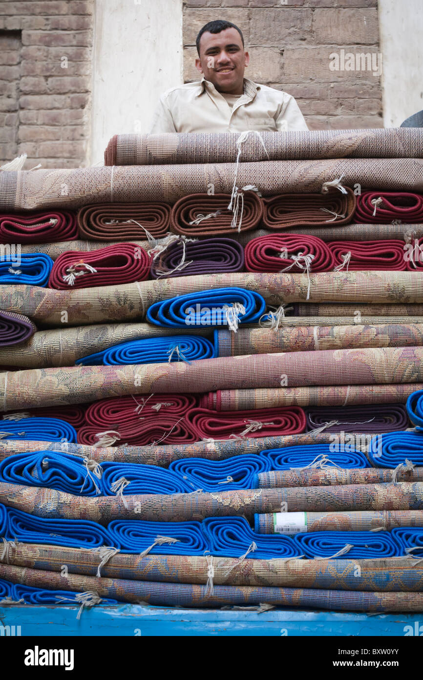 Carpet seller on top of carpet pile on the back of a truck at a local ...