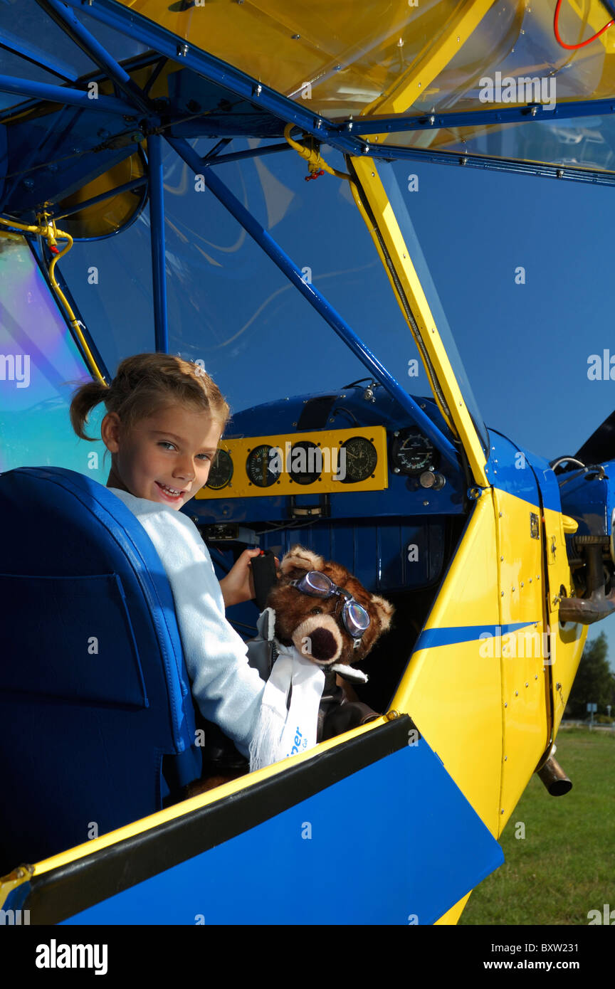 Young girl with her teddy bear pilot in the cockpit of the famous Piper ...