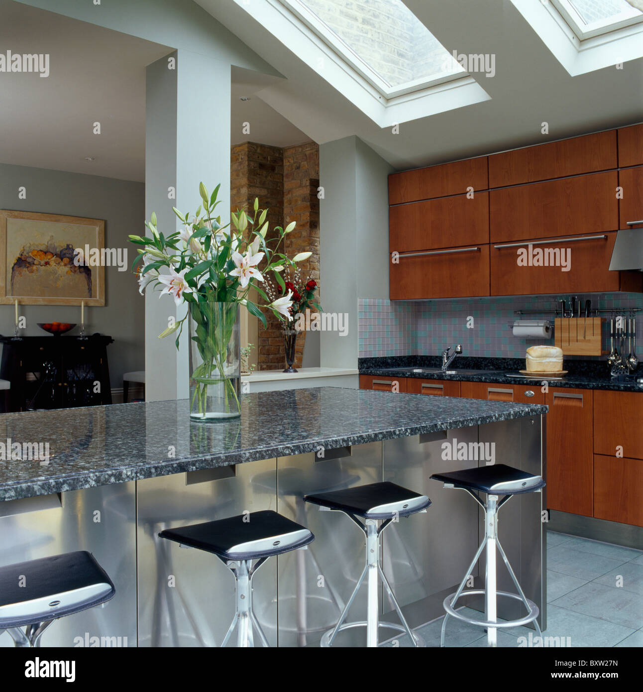 Chrome stools at granite-topped breakfast bar in large modern kitchen ...