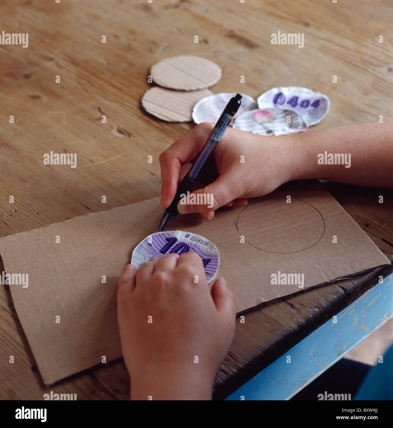 Close-up of hands cutting round old car license sticker Stock Photo - Alamy