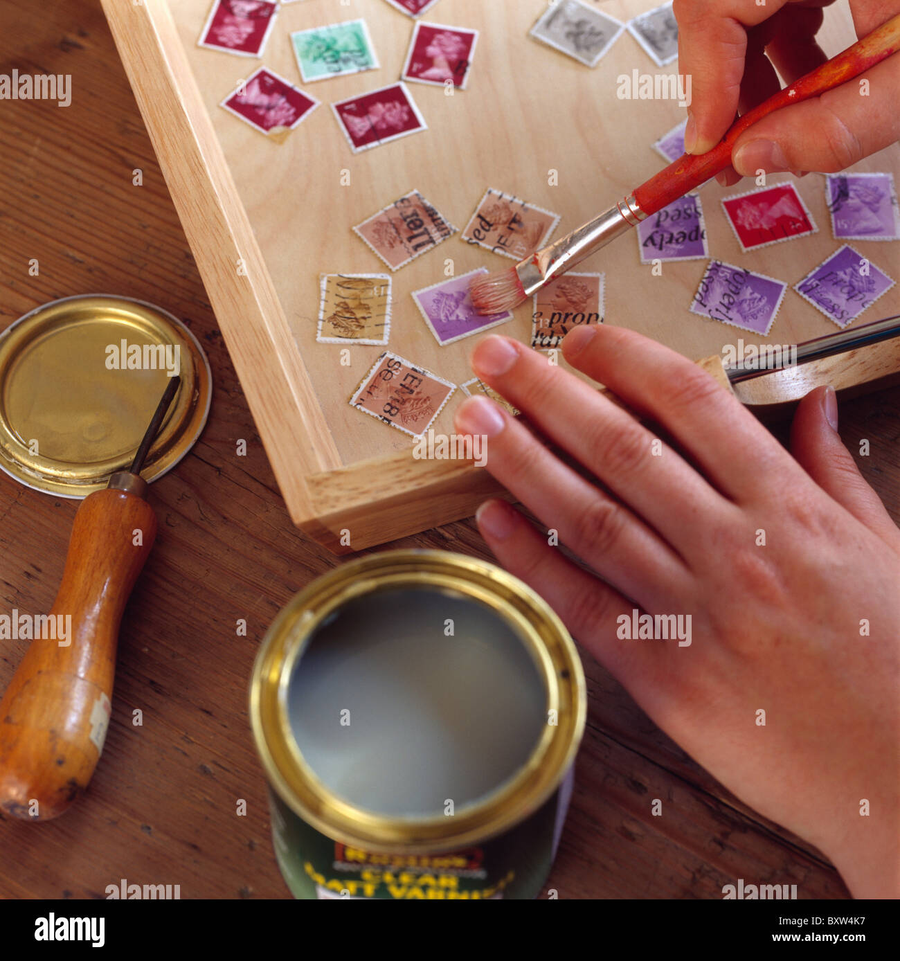 Close-up of hands glueing stamps onto wooden table Stock Photo - Alamy
