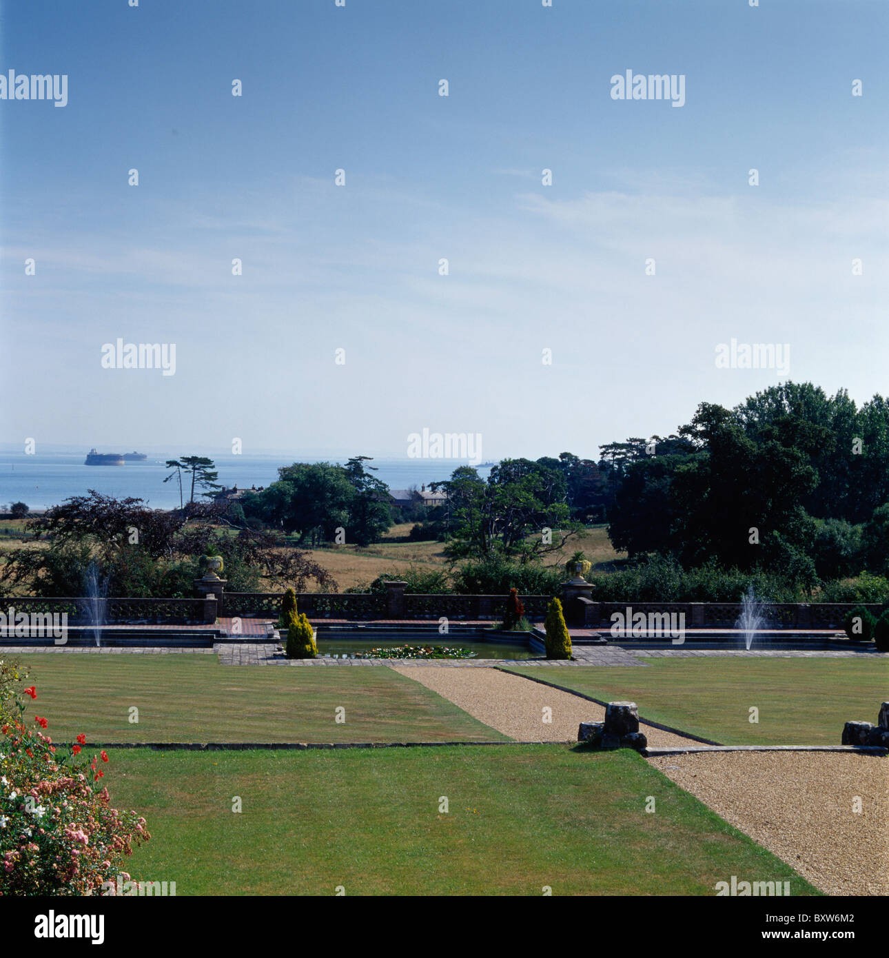 Wide gravel path between split-level lawns in large coastal garden in ...