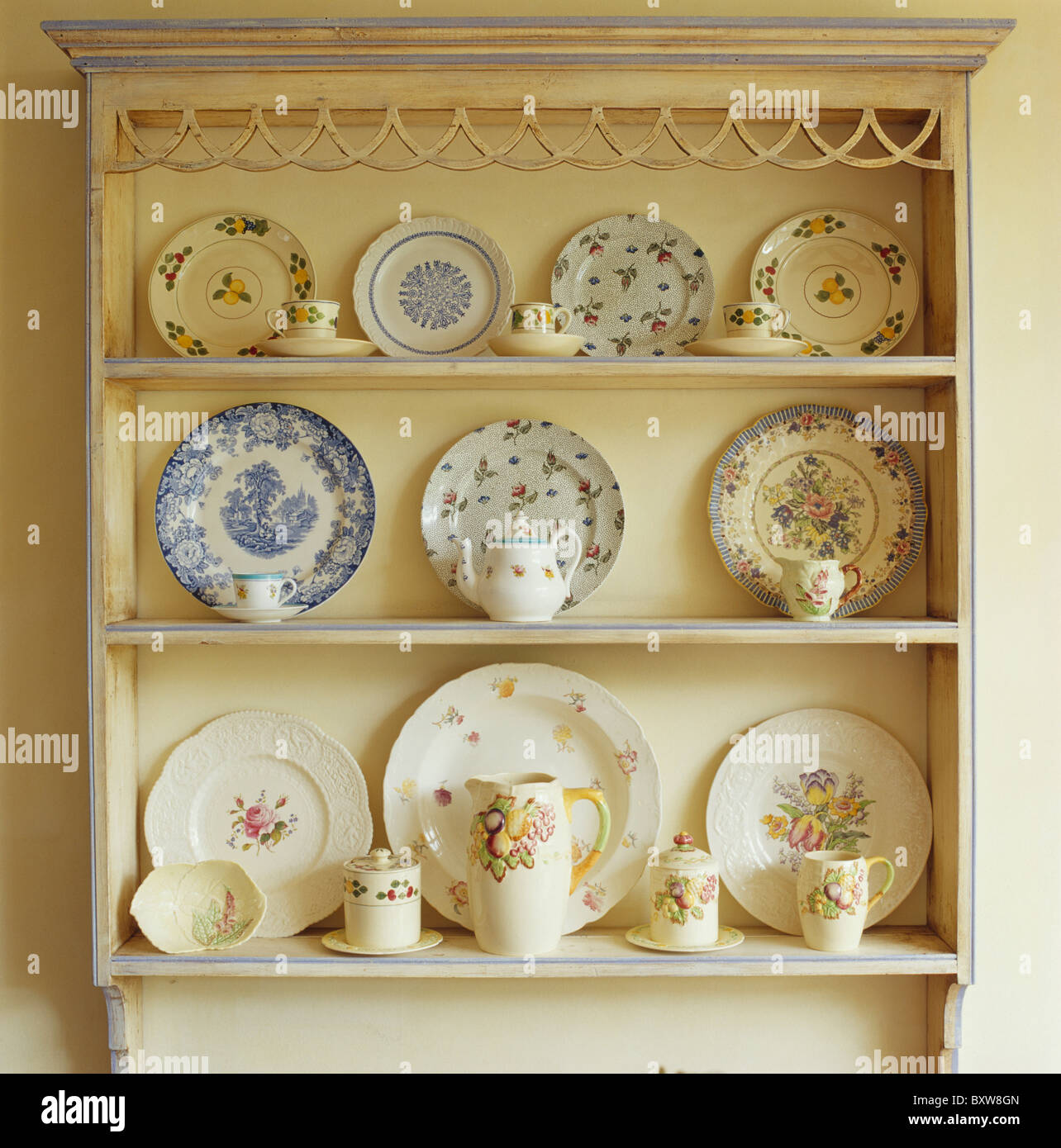 Close-up of collection of antique china plates on cream painted shelves ...