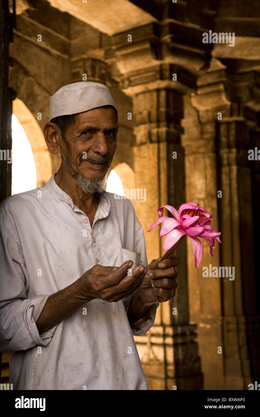 A Muslim man holds a pink lotus flower at the Bai Harir Mosque at ...