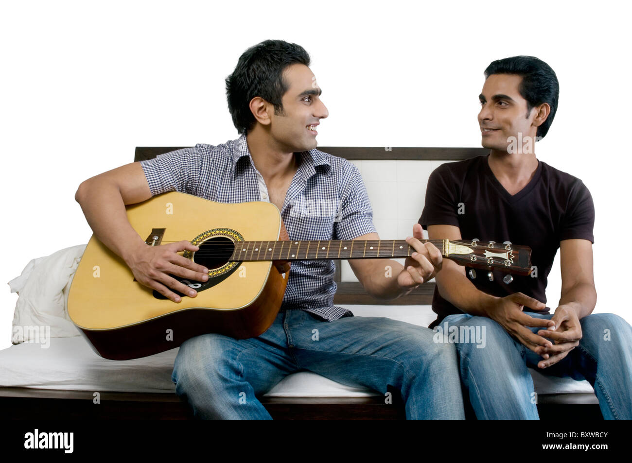 two men sitting on a bed Stock Photo - Alamy