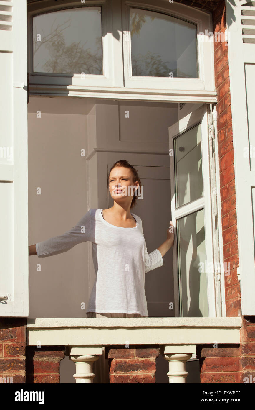 Young woman opening window Stock Photo - Alamy