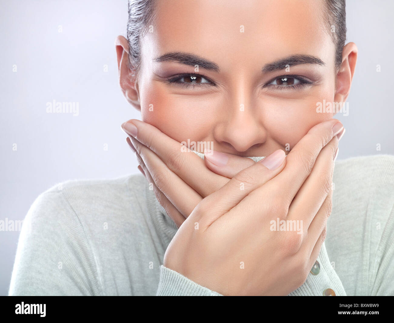 Young woman with hands covering mouth Stock Photo - Alamy