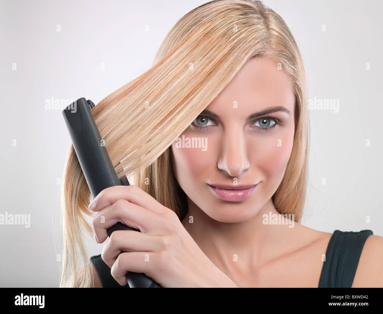 Young woman using hair straighteners Stock Photo - Alamy
