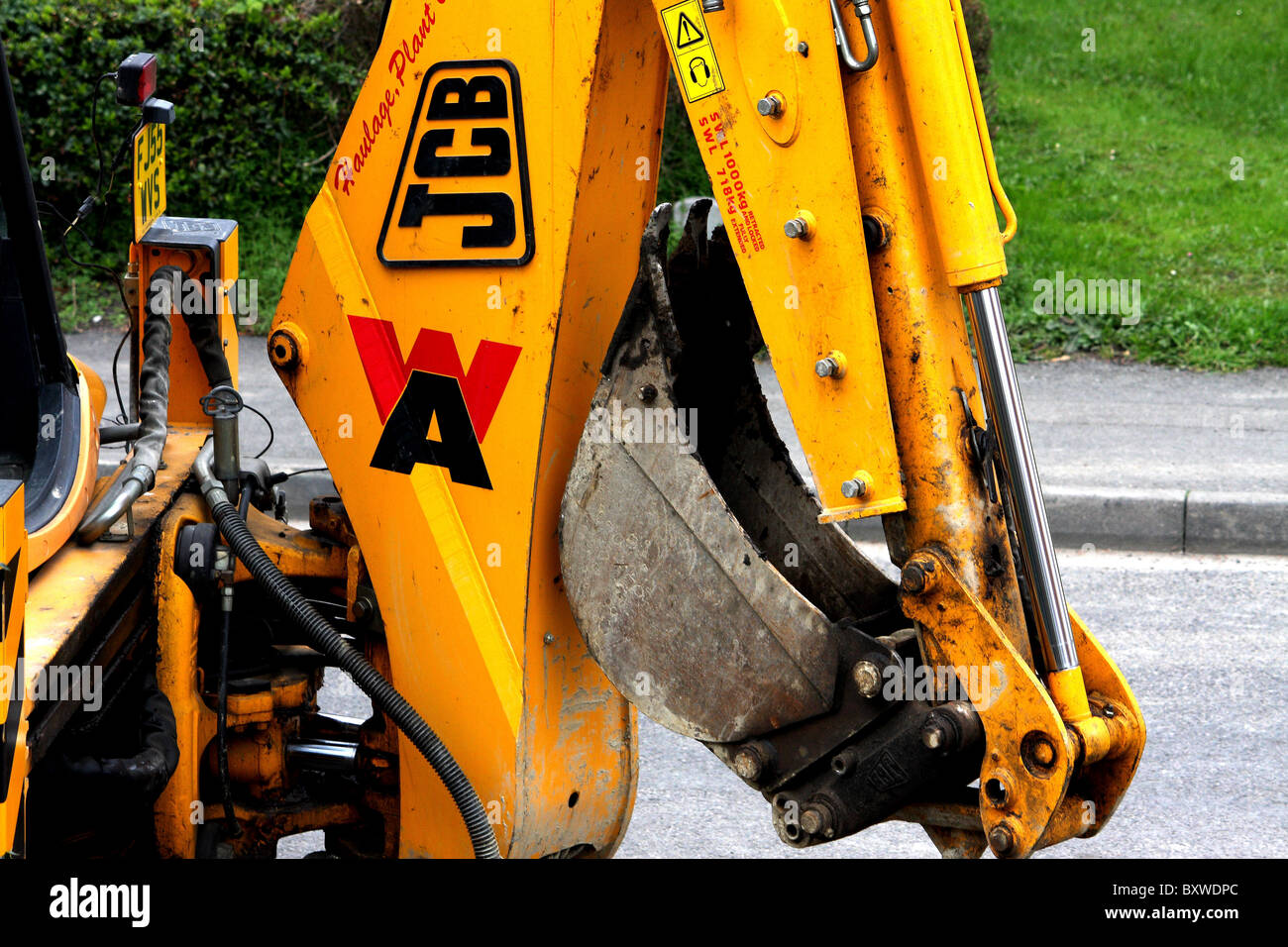 A JCB digging a local streets road up for roadworks to take place Stock ...